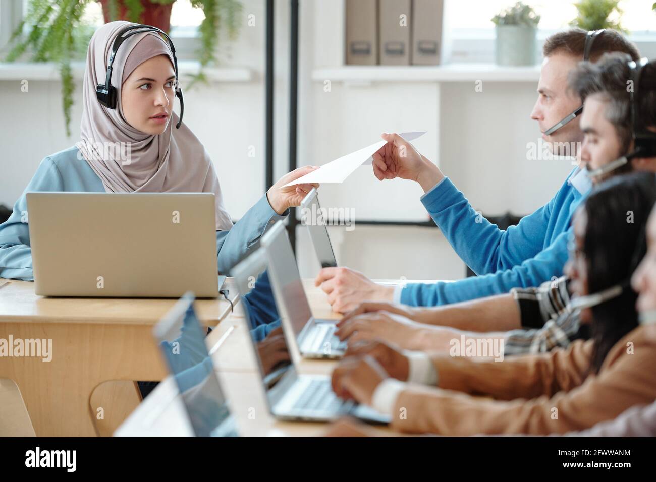 Serious young Arabian woman in hijab giving script to call center ...