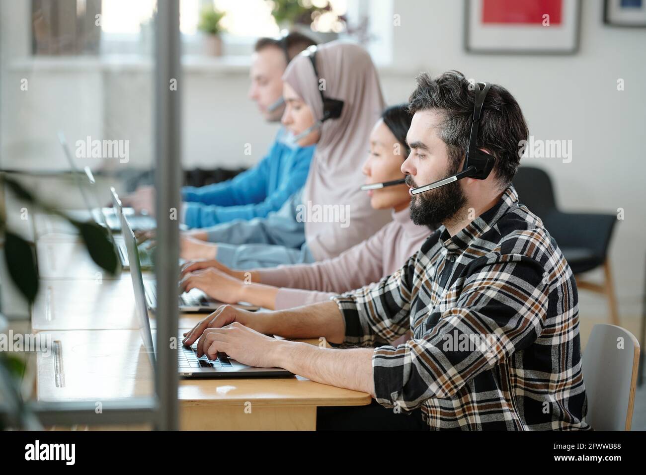 Row of busy multi-ethnic call center operators in headset with ...