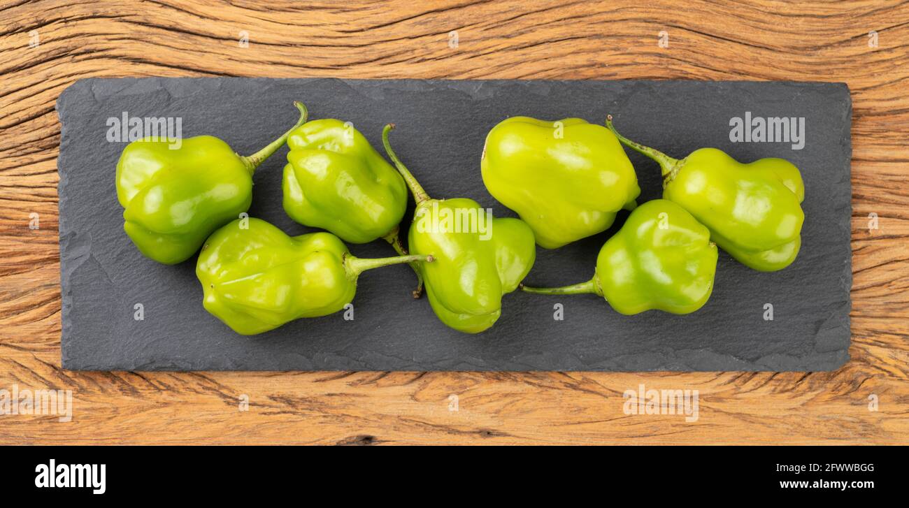 Green cambuci peppers on a stone board over wooden table. Typical ...
