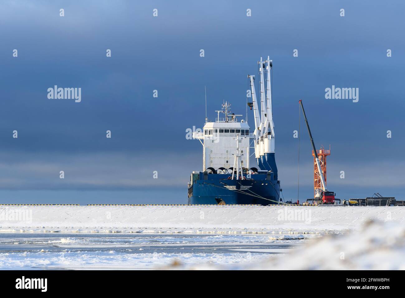 Cargo vessel moored in arctic port. Winter time. Ice navigation ...