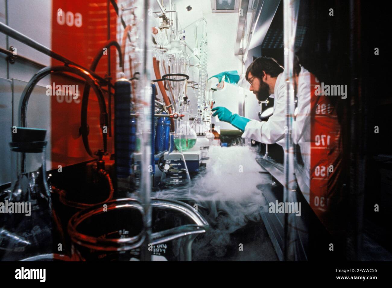 A chemist with lab equipment; glassware; graduated cylinders; hood; dry ...