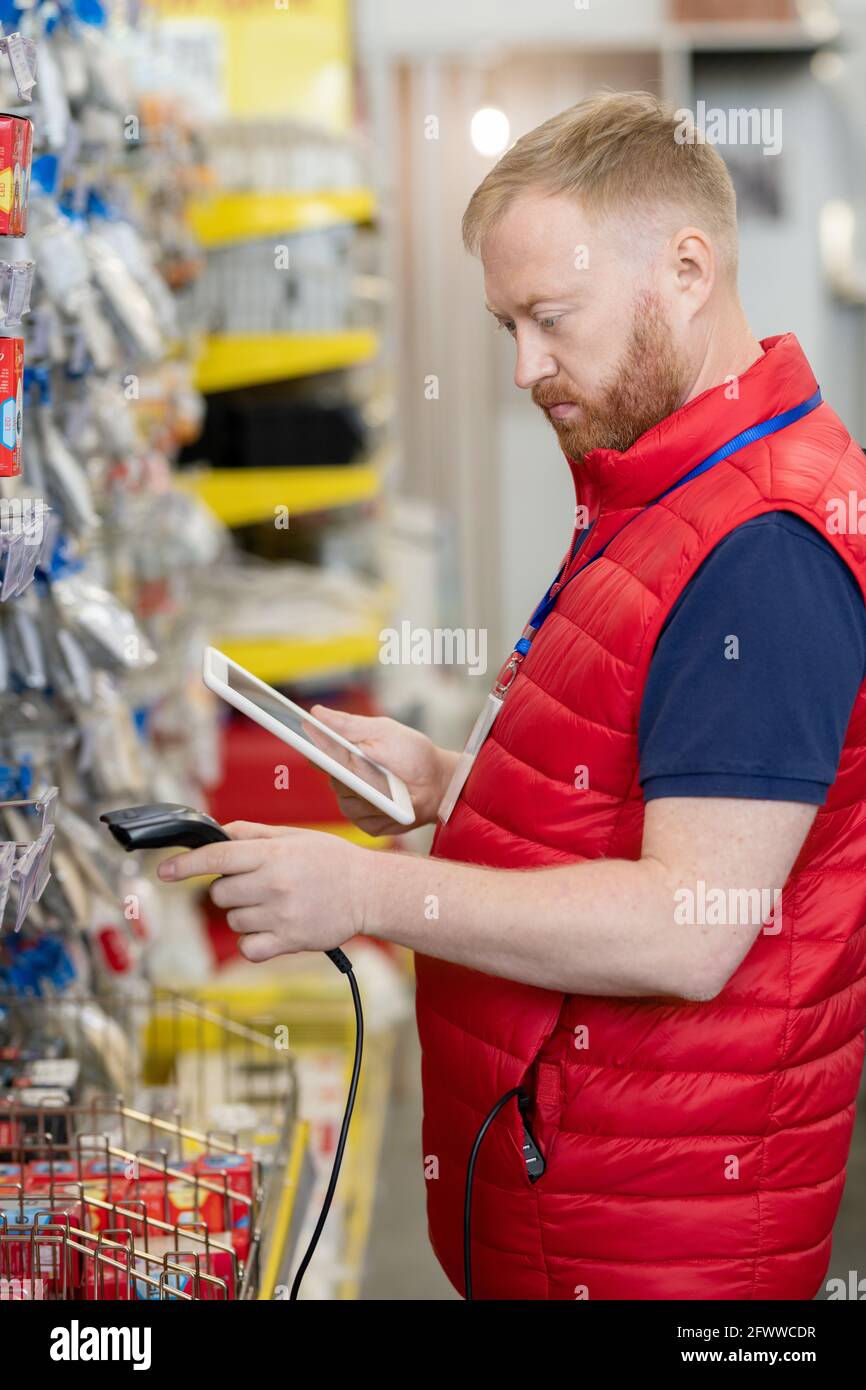 Shop assistant with tablet scanning goods on display Stock Photo - Alamy