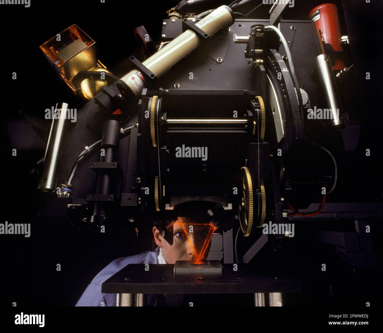 A worker measures the flatness of an optical mirror using laser light ...