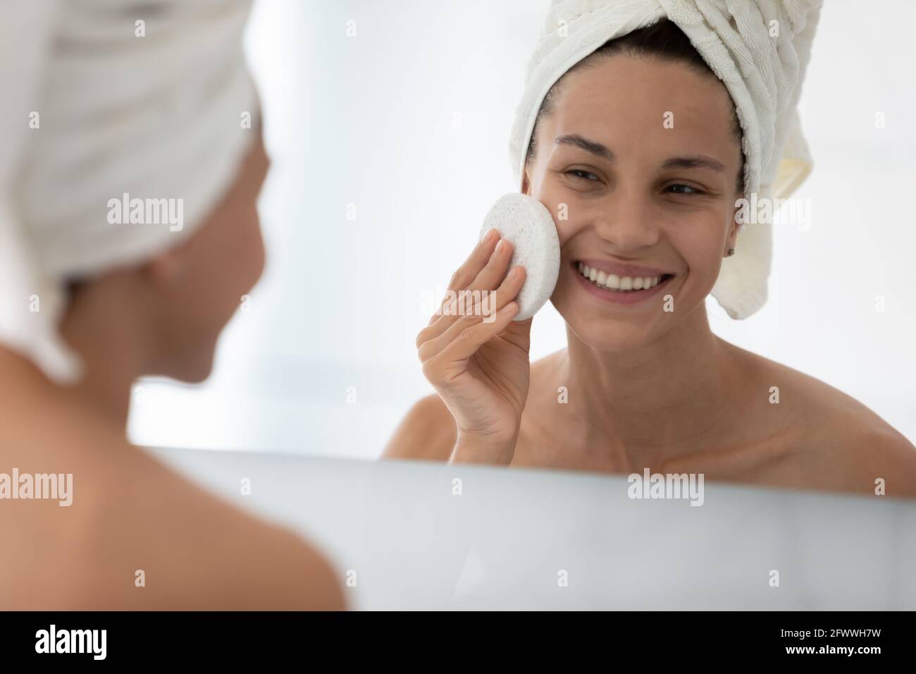 Happy beautiful girl cleansing facial skin with skincare exfoliating ...