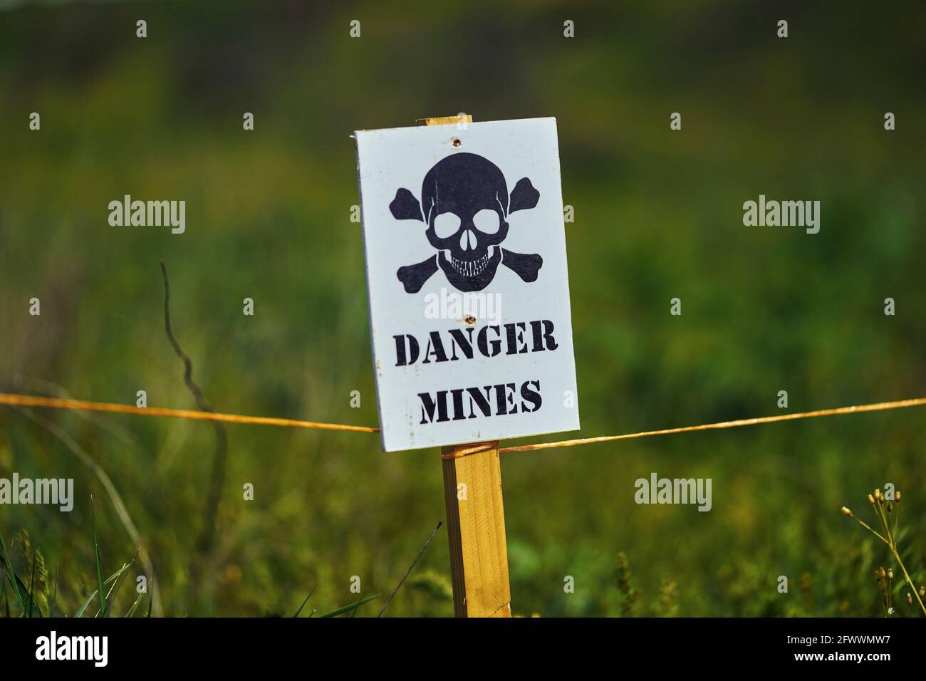 Close-up of a yellow sign with a skull warning of danger in a minefield ...