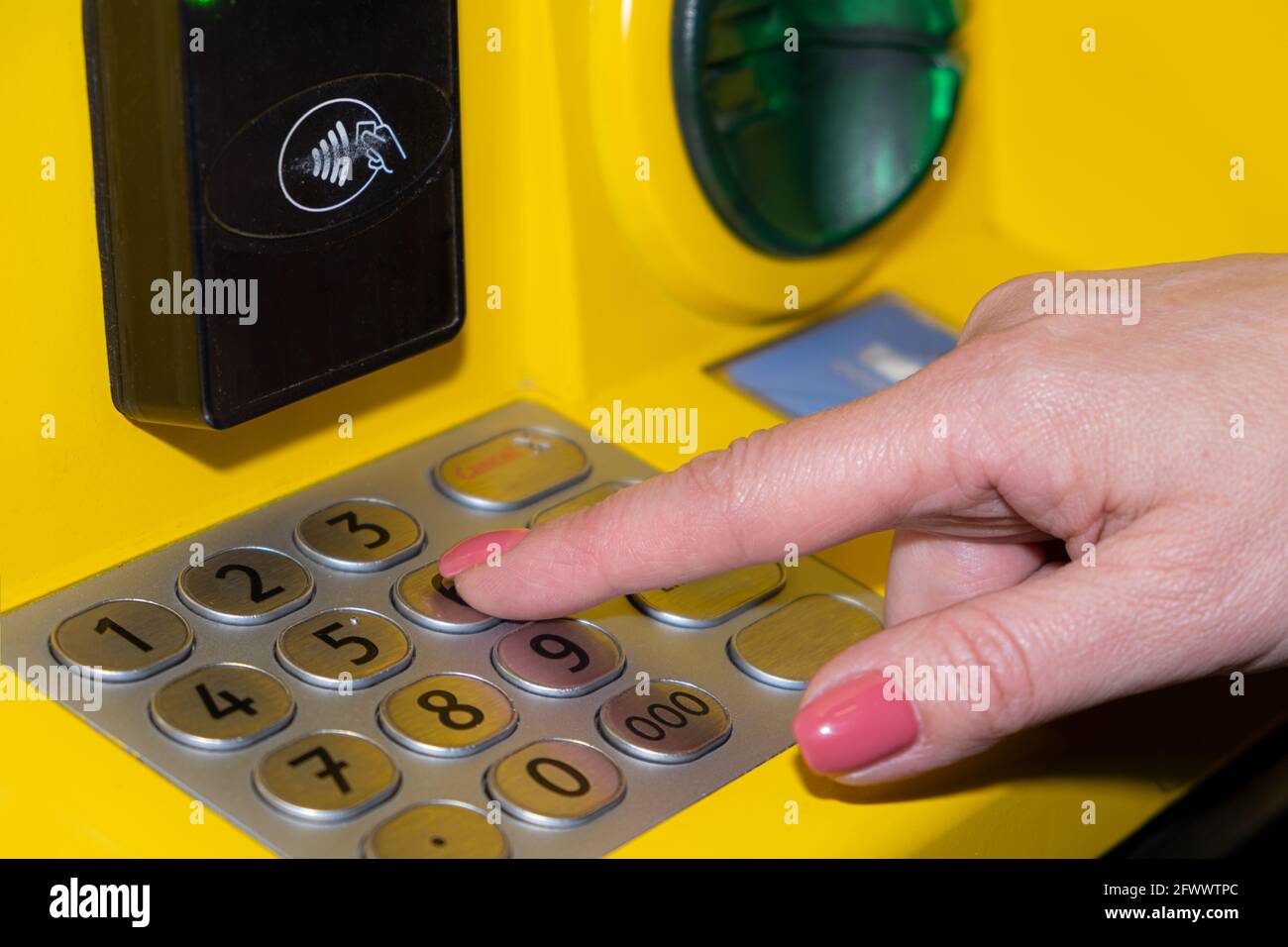 A woman's hand dials the PIN code on the bank's ATM. A young woman ...