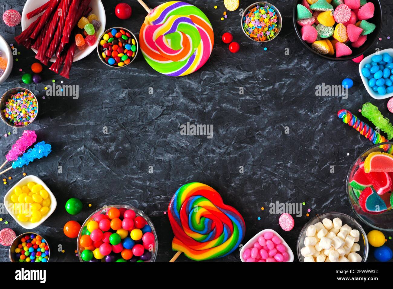 Sweet and colorful candy buffet frame. Top view table scene over a dark ...