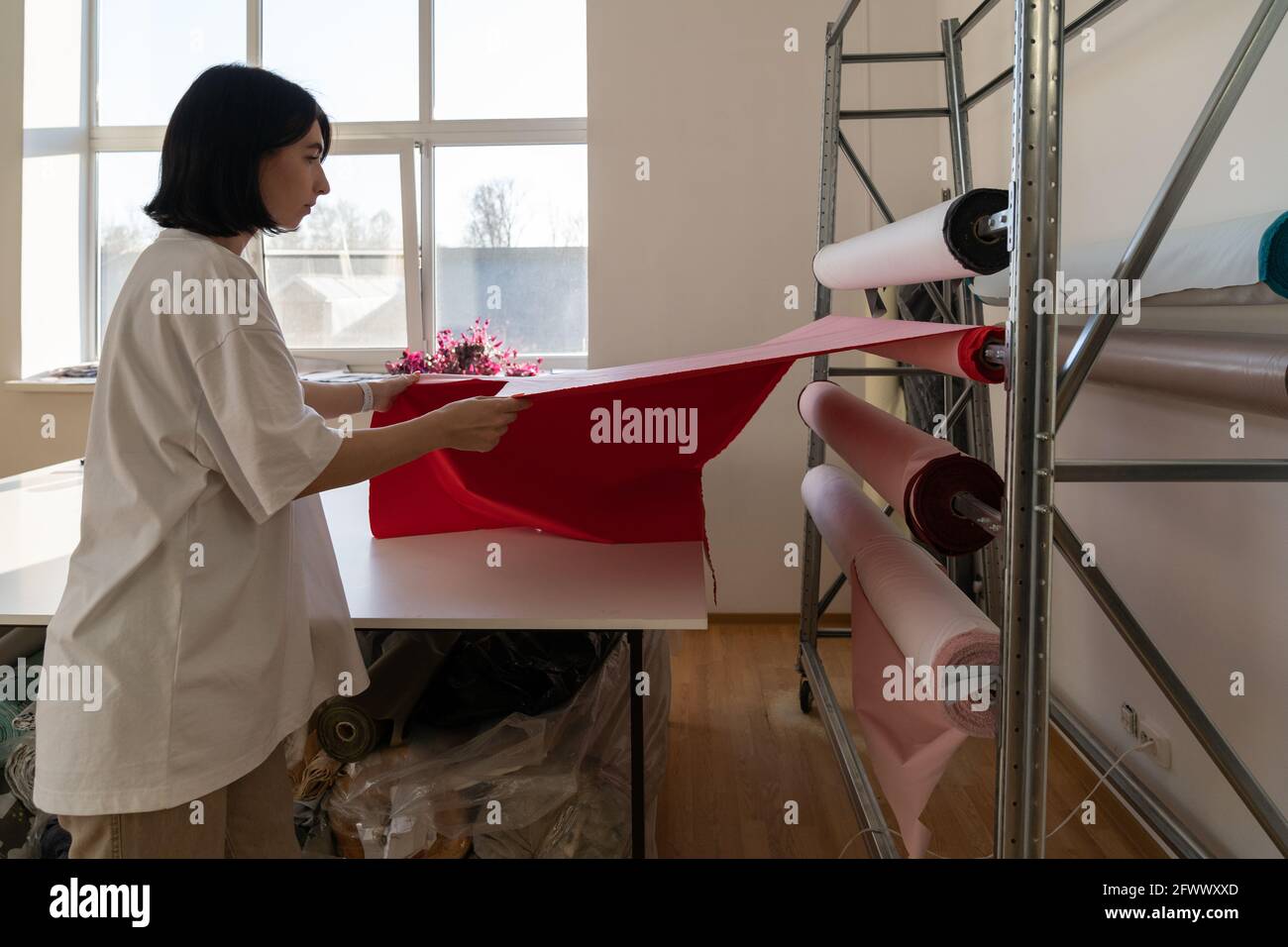 Girl professional tailor choose fabric roll for cutting. Designer ...