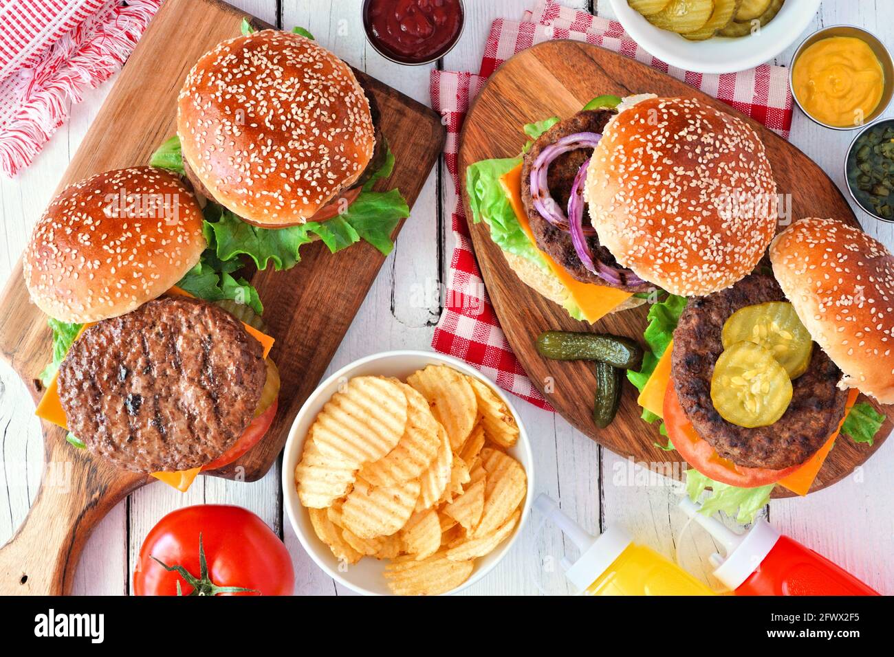 BBQ hamburger table scene. Top down view over a white wood background ...