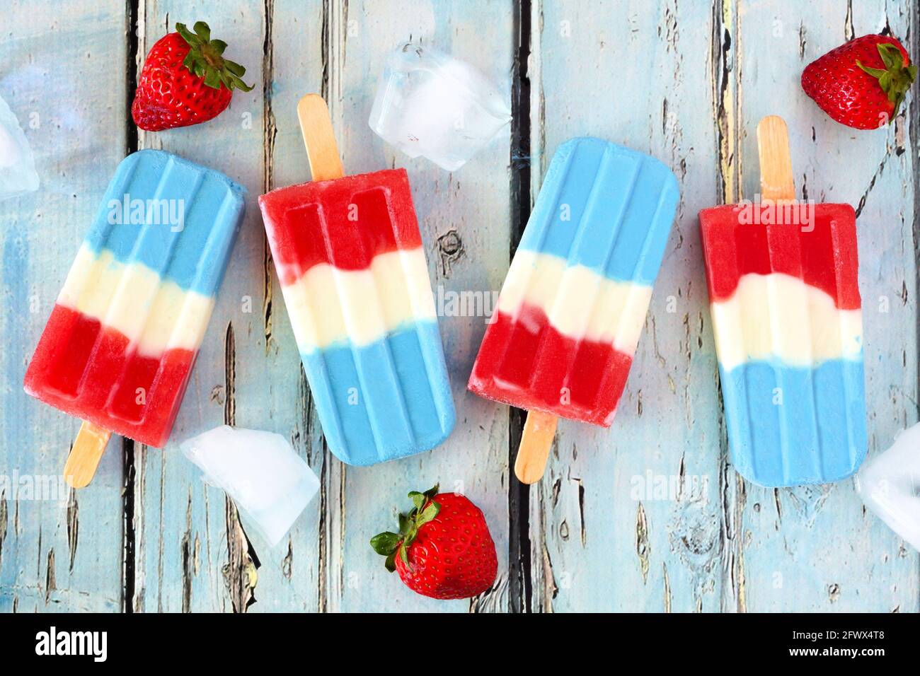 Red, white and blue summer fruit ice pops. Top view on a rustic blue ...