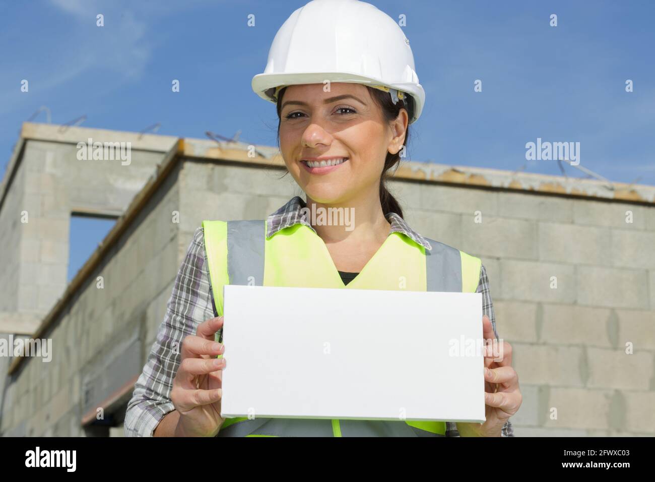 attractive female builder showing blank sign Stock Photo - Alamy