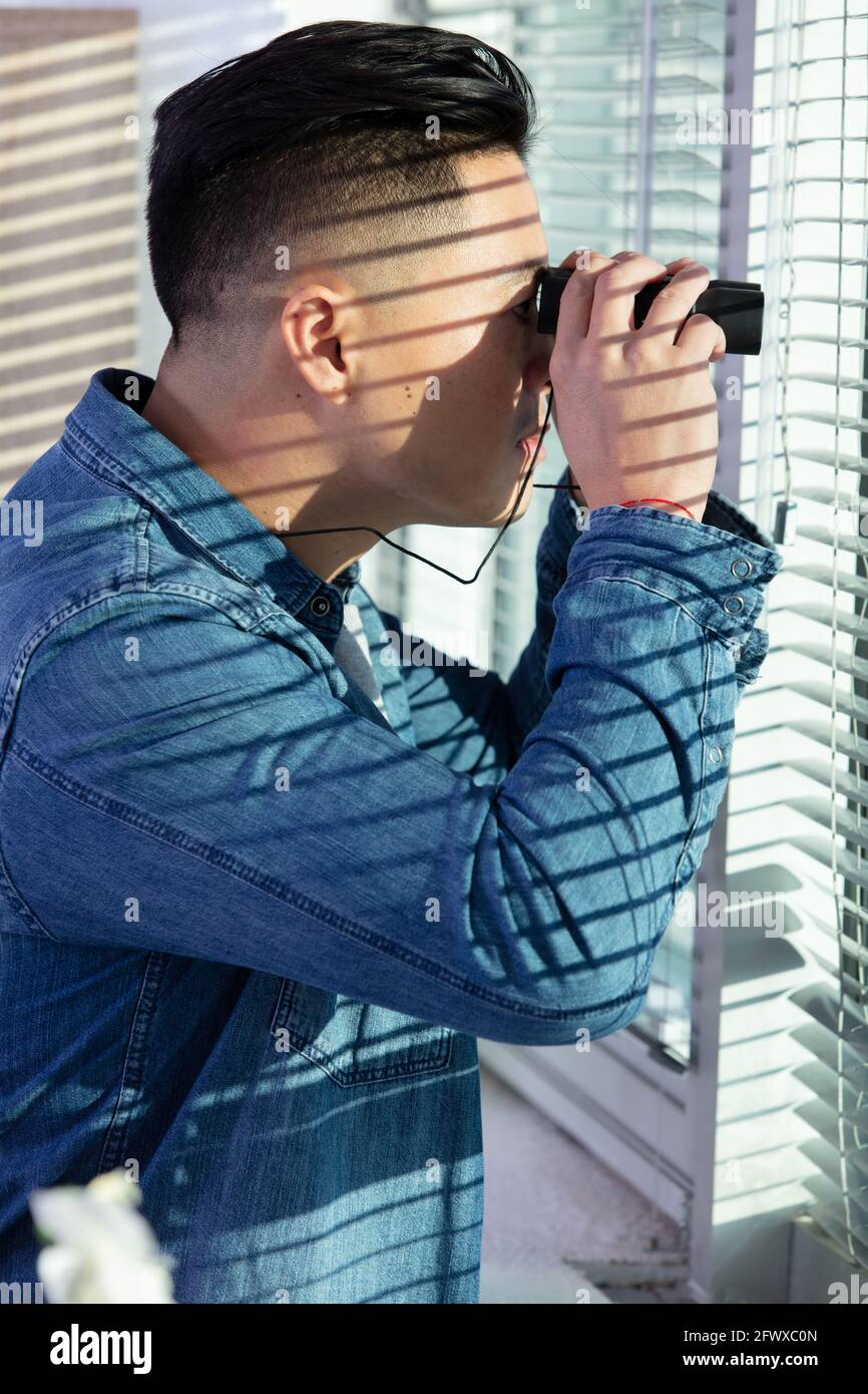 young man standing looking through a glass window with binoculars Stock ...