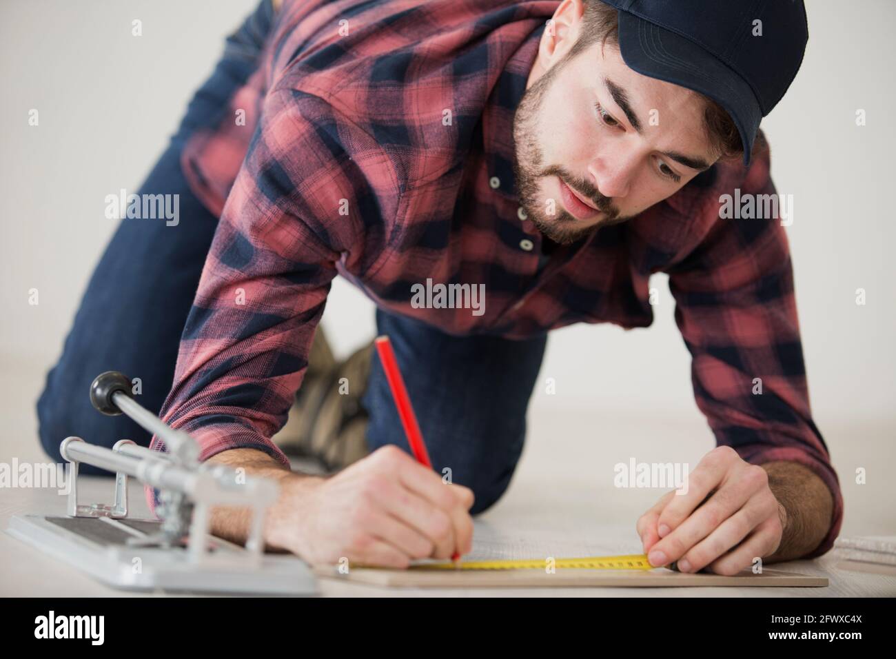 man using a pencil for measuring flooring plank Stock Photo - Alamy