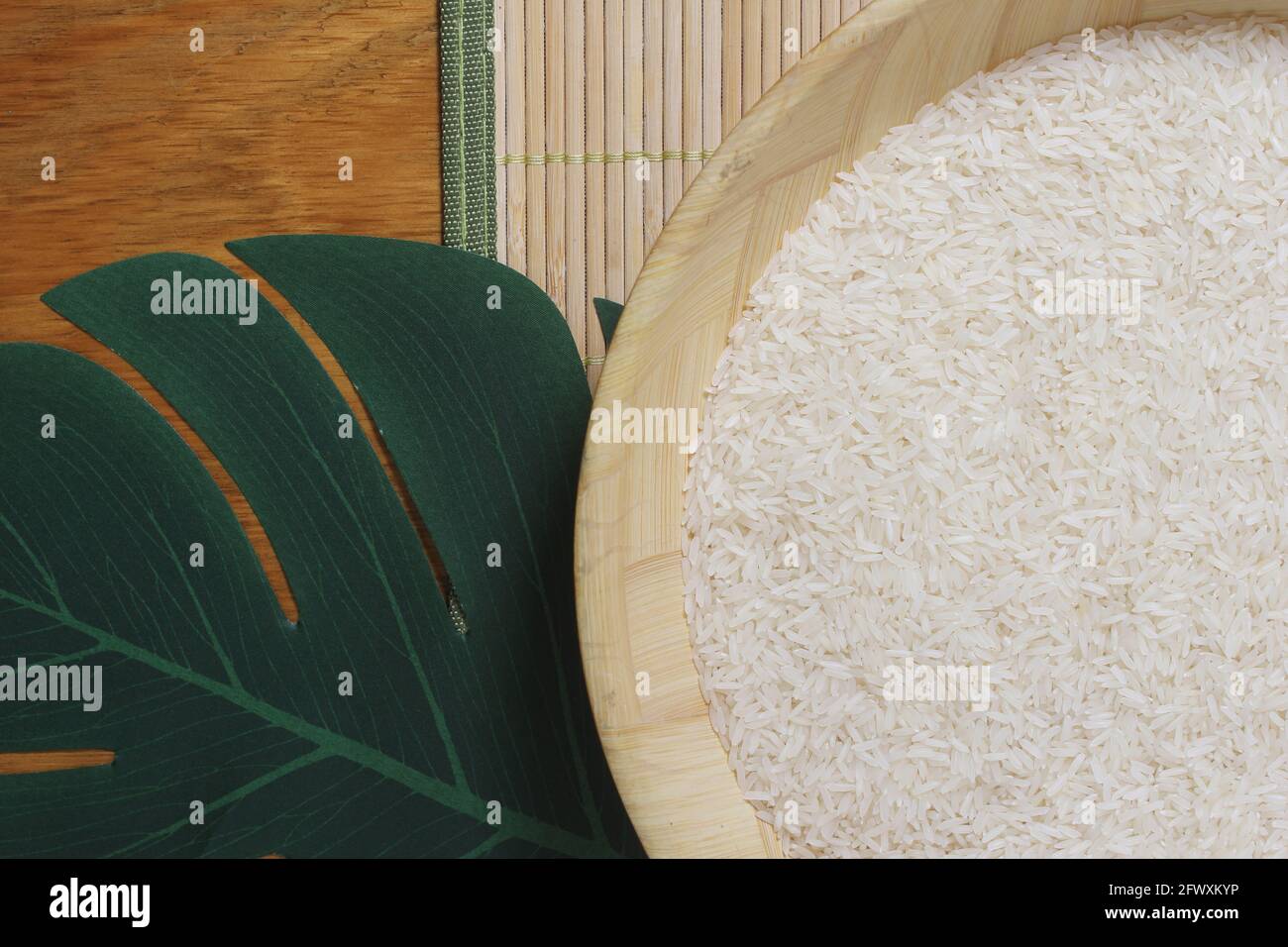 Bowl of Uncooked White Rice with leaf on bamboo mat Stock Photo - Alamy