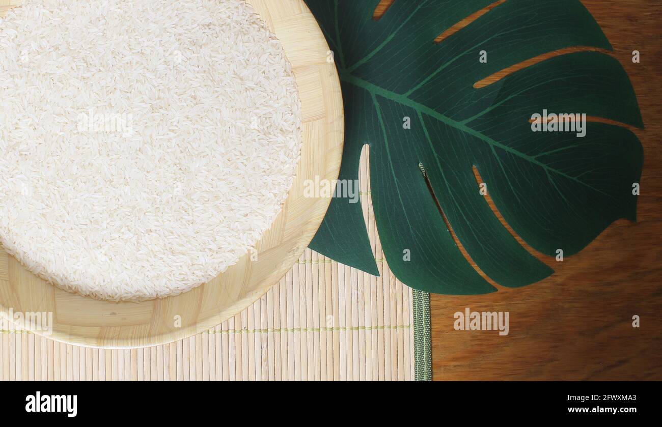 Bowl of Uncooked White Rice with leaf on bamboo mat Stock Photo - Alamy