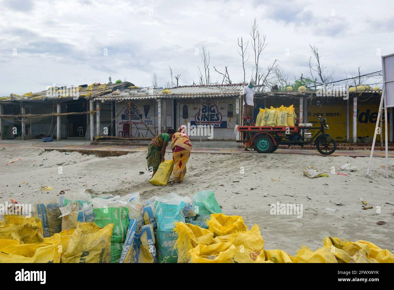 Women collect sand bags to make temporary embankments in front of their ...