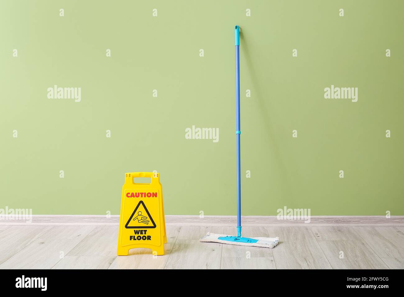 Floor mop and caution sign near color wall Stock Photo - Alamy