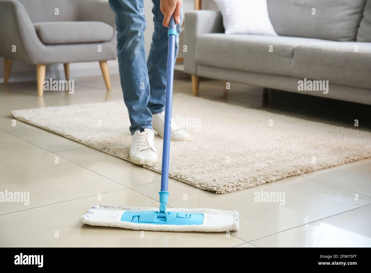 Young man mopping floor in living room Stock Photo - Alamy