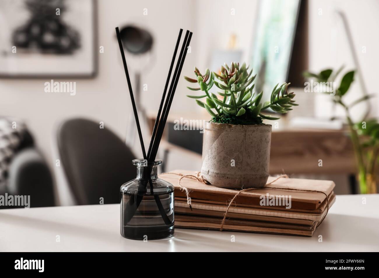Reed diffuser with houseplant and notebooks on table in room Stock ...