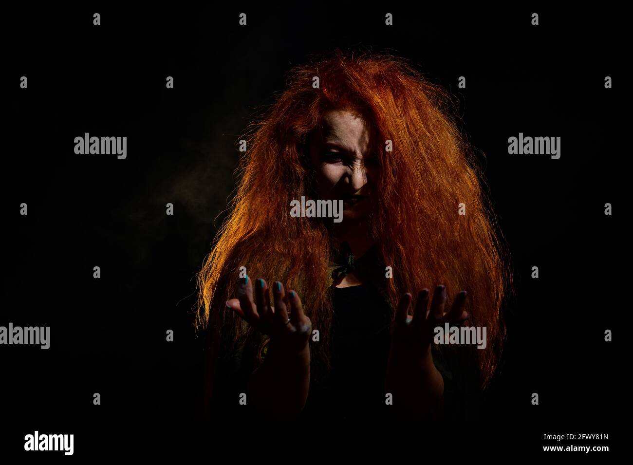 Portrait of an evil red-haired witch conjures in the dark Stock Photo ...