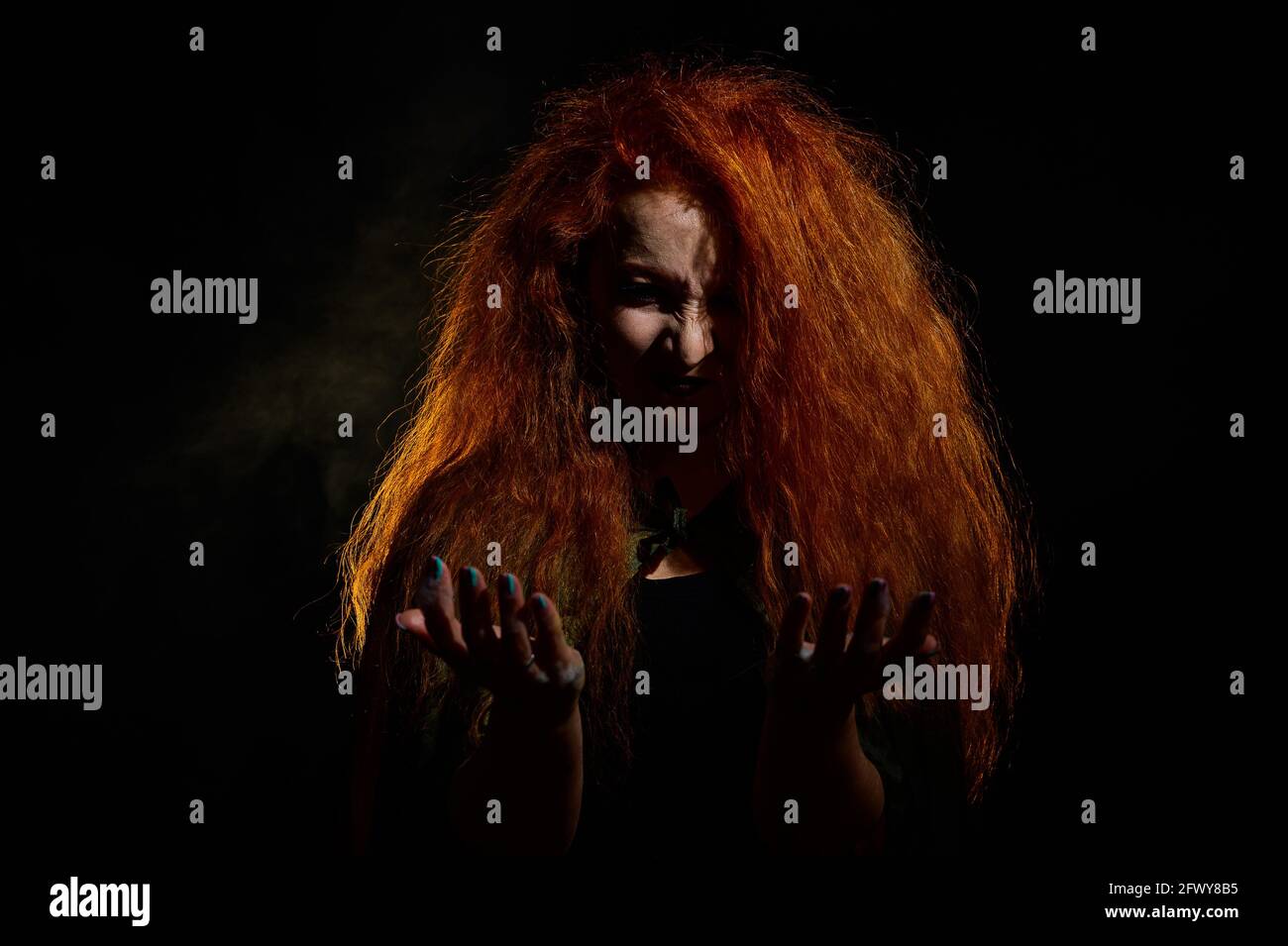 Portrait of an evil red-haired witch conjures in the dark Stock Photo ...