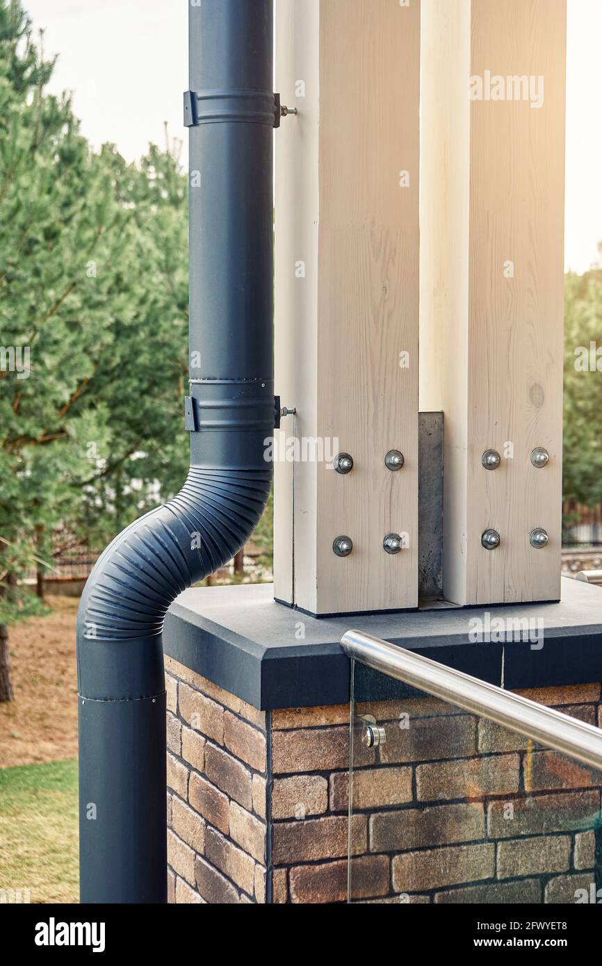 Support of wooden poles for roof with rainwater downpipe on concrete ...