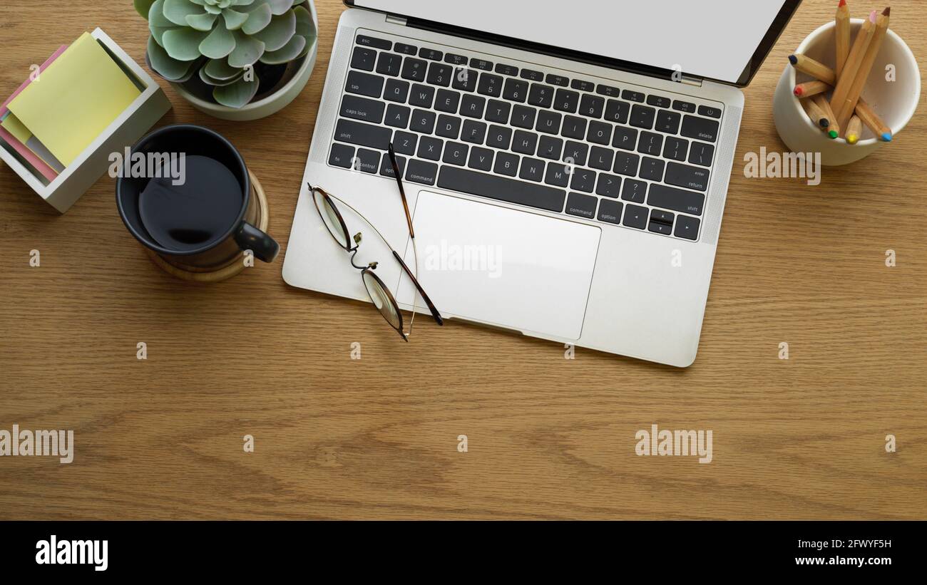Wooden table with laptop, coffee cup, stationery and eyeglasses in home ...