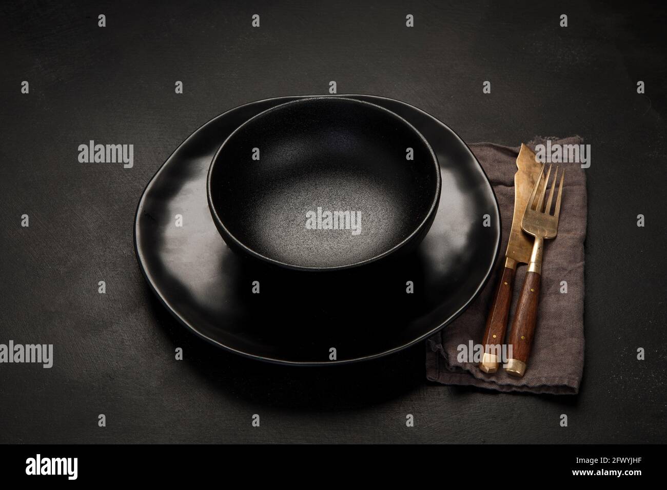 Table setting with a black plates on a black background. Minimalism ...