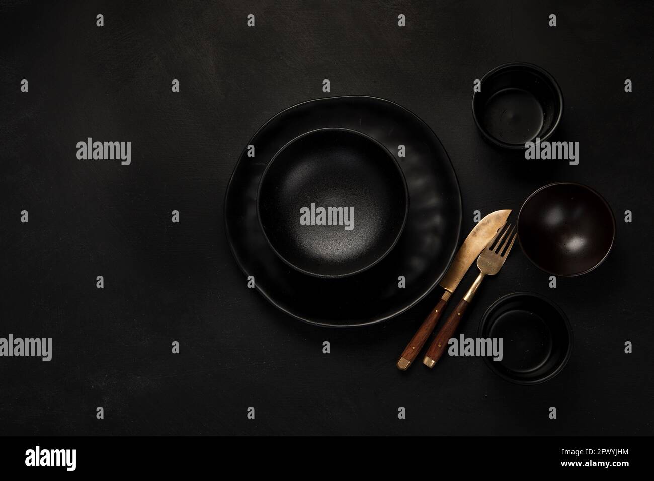 Table setting with a black plates on a black background. Minimalism ...