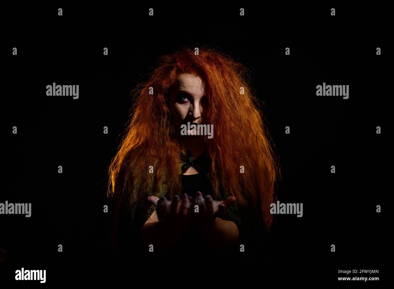 Portrait of an evil red-haired witch conjures in the dark Stock Photo ...