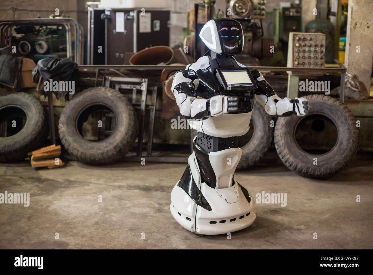 A humanoid, white robot on wheels, with a display on his chest, moves ...