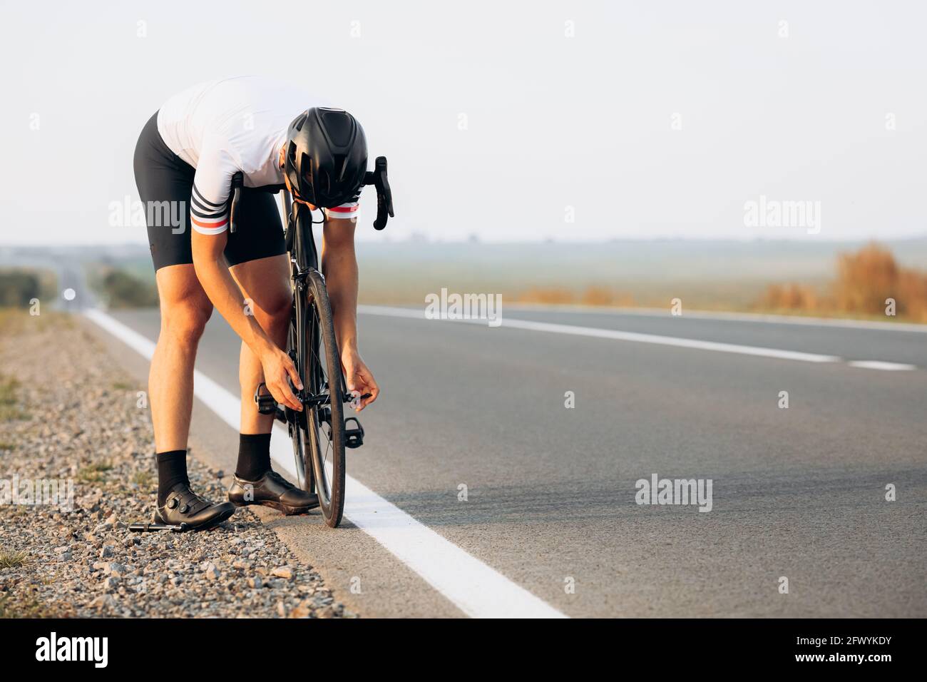 Professional cyclist standing on road and fixing his bike Stock Photo ...