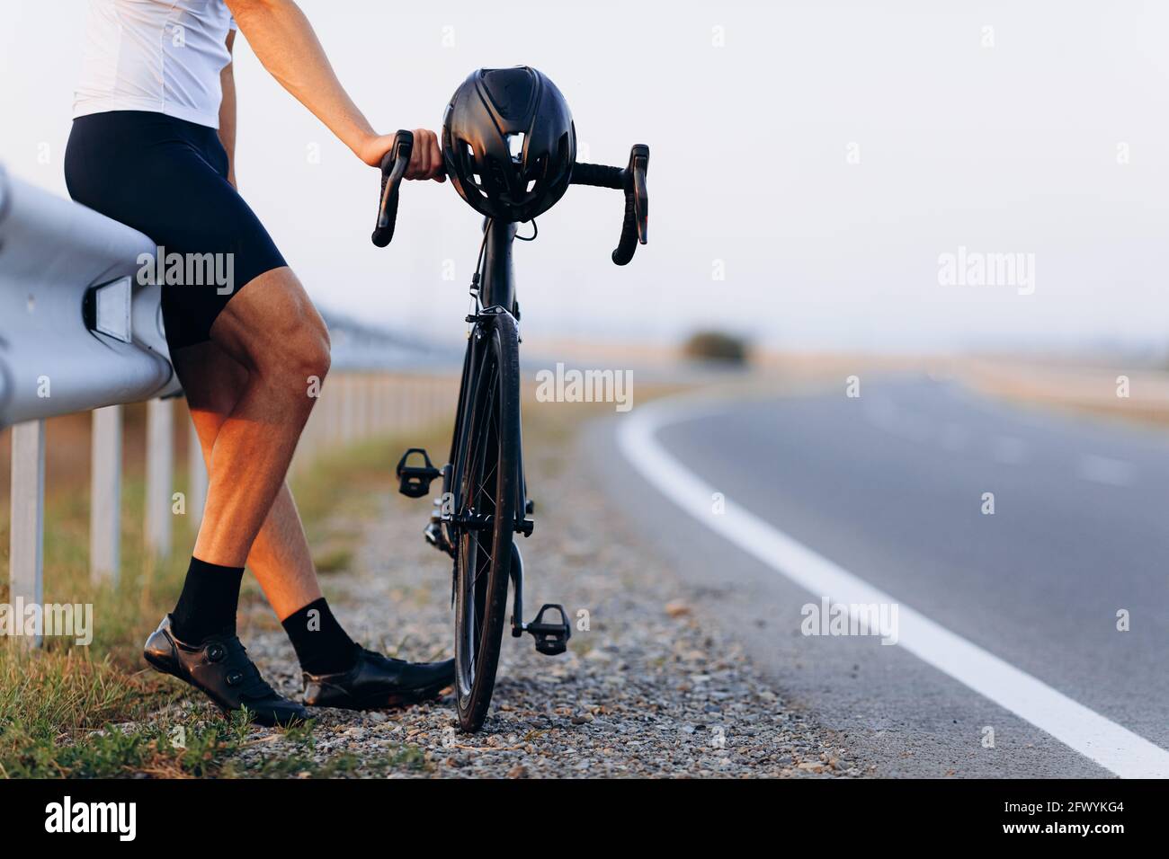 Muscular cyclist relaxing on asphalt road after racing Stock Photo - Alamy