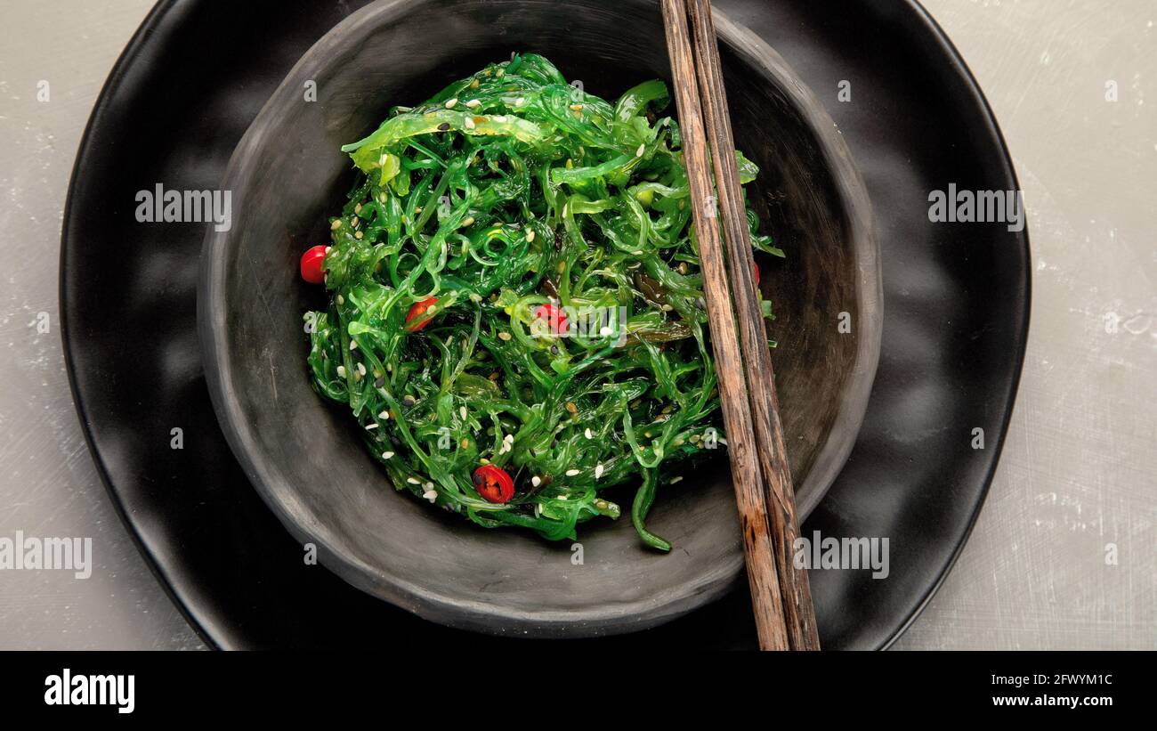 Wakame seaweed with sesame and chilli on gray background. Asian food ...