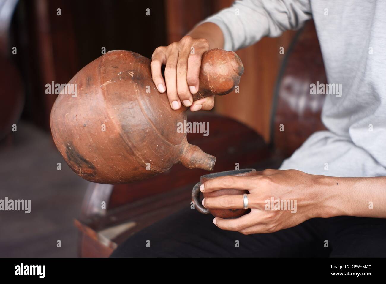 men's hands holding pots and cups made in clay. traditional Javanese ...