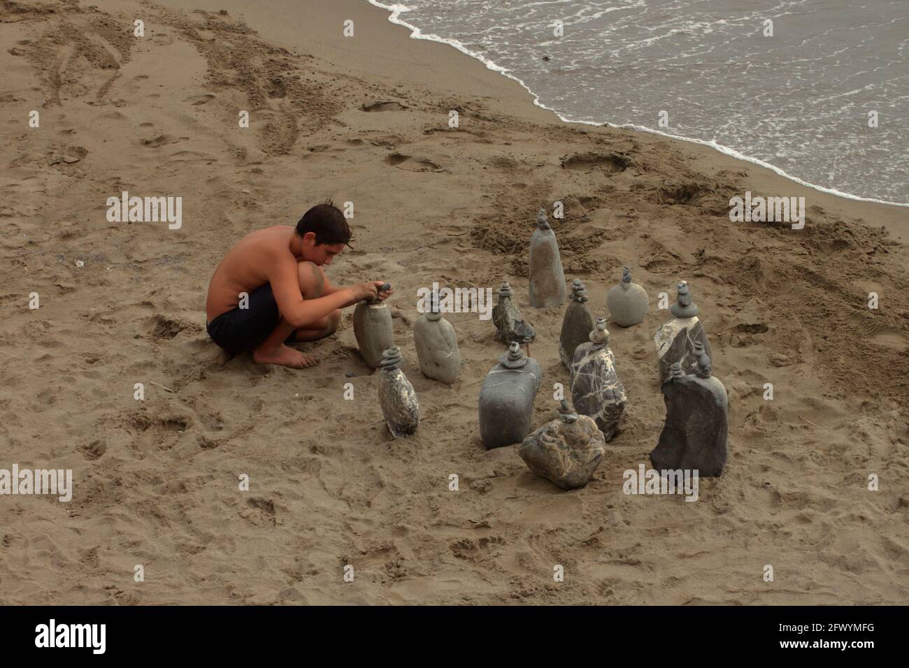 Man on beach balancing rocks hi-res stock photography and images - Alamy