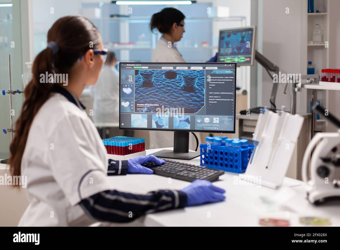 Biologist doctor checking DNA informations typing on pc in modern ...