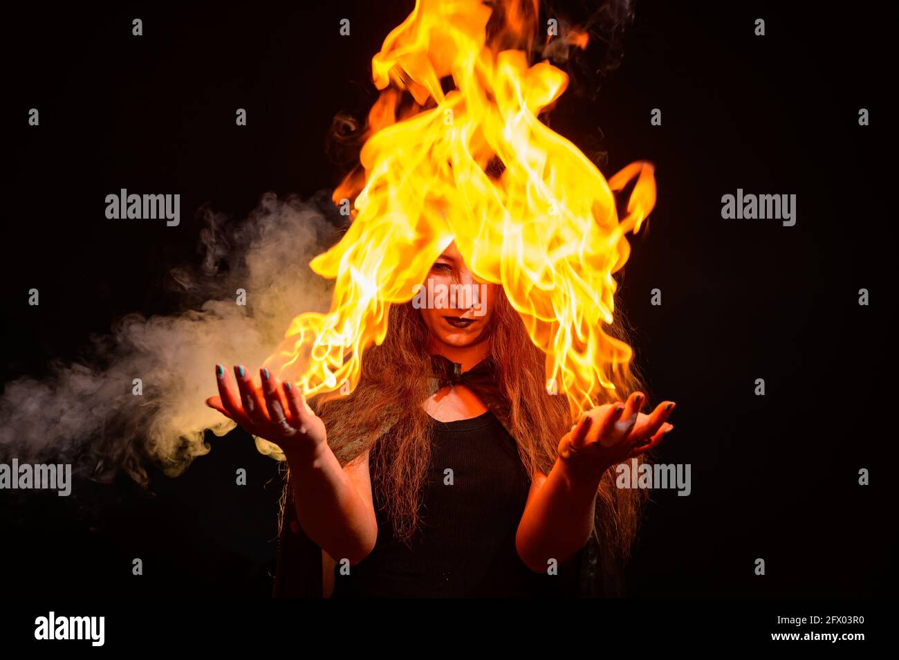 An evil red-haired witch holds fire in her hands Stock Photo - Alamy