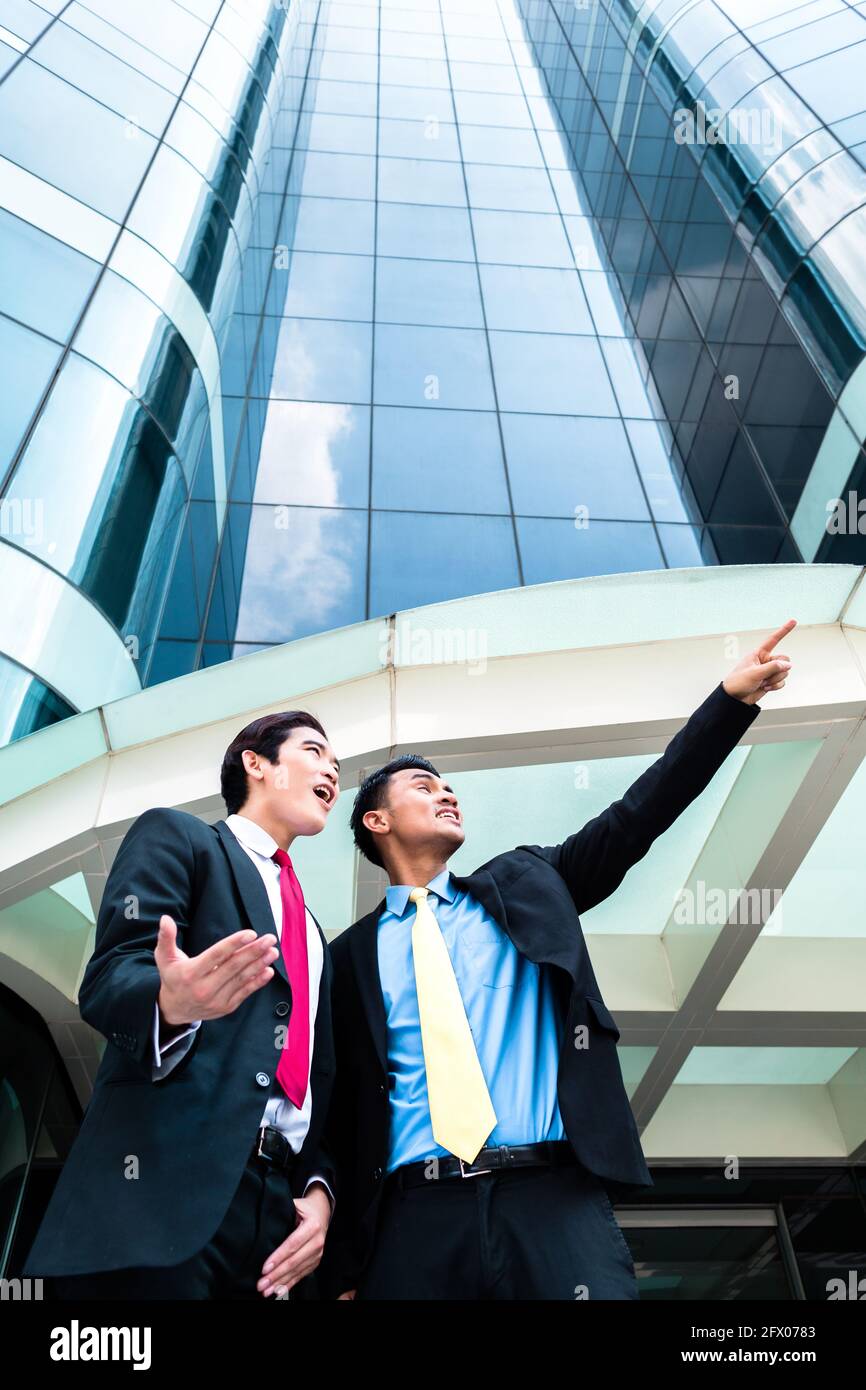 Asian business men outside in front of tower building Stock Photo - Alamy