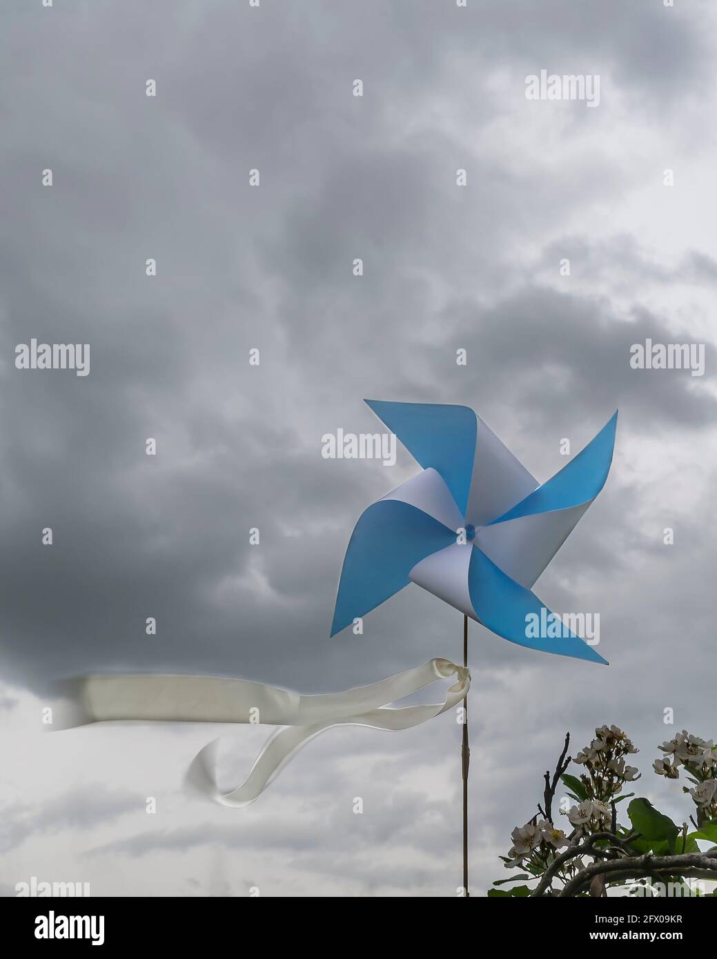 A blue and white pinwheel with a ribbon blowing in the wind against a ...