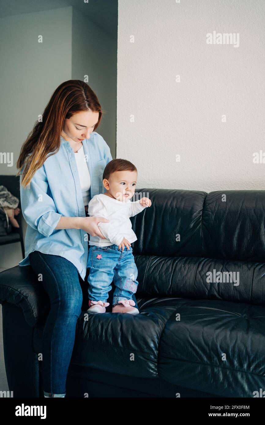 Focused young mother in casual wear teaching adorable little baby to ...