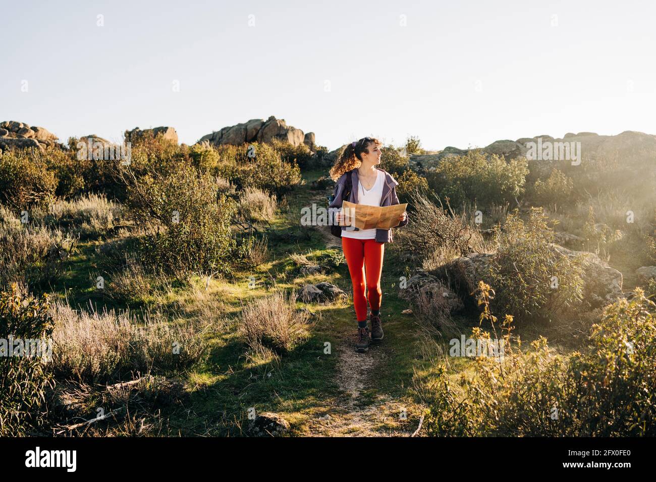 Full body of focused young female explorer in casual clothes reading ...