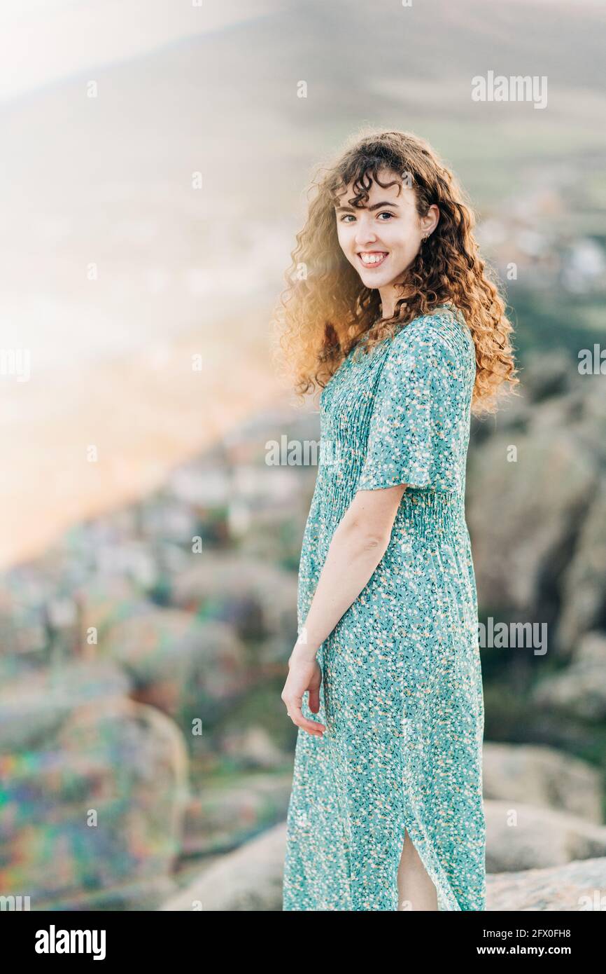 Full body attractive cheerful female in maxi sundress standing barefoot ...