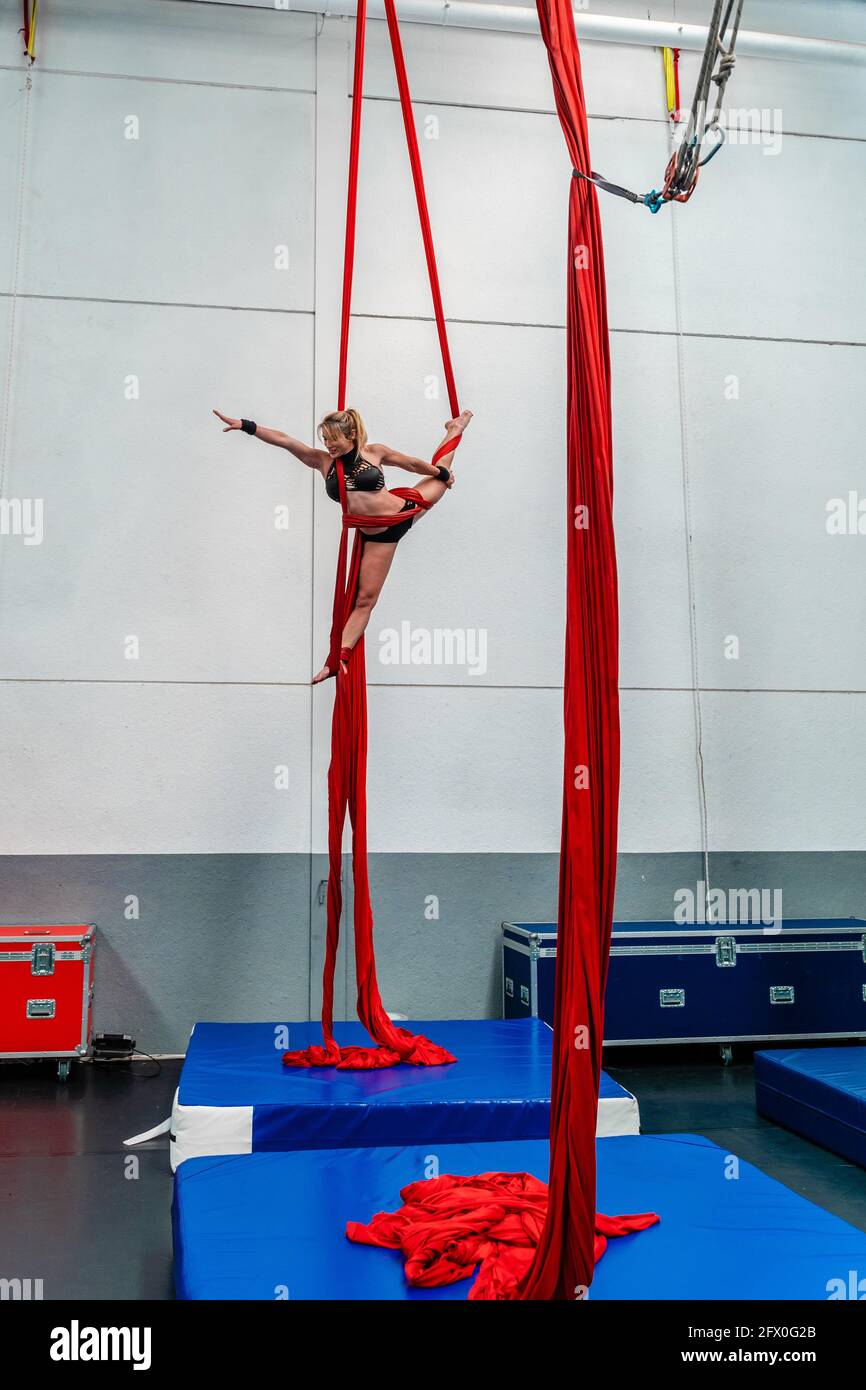 Full length slim agile sportsWoman in activewear doing split on red ...