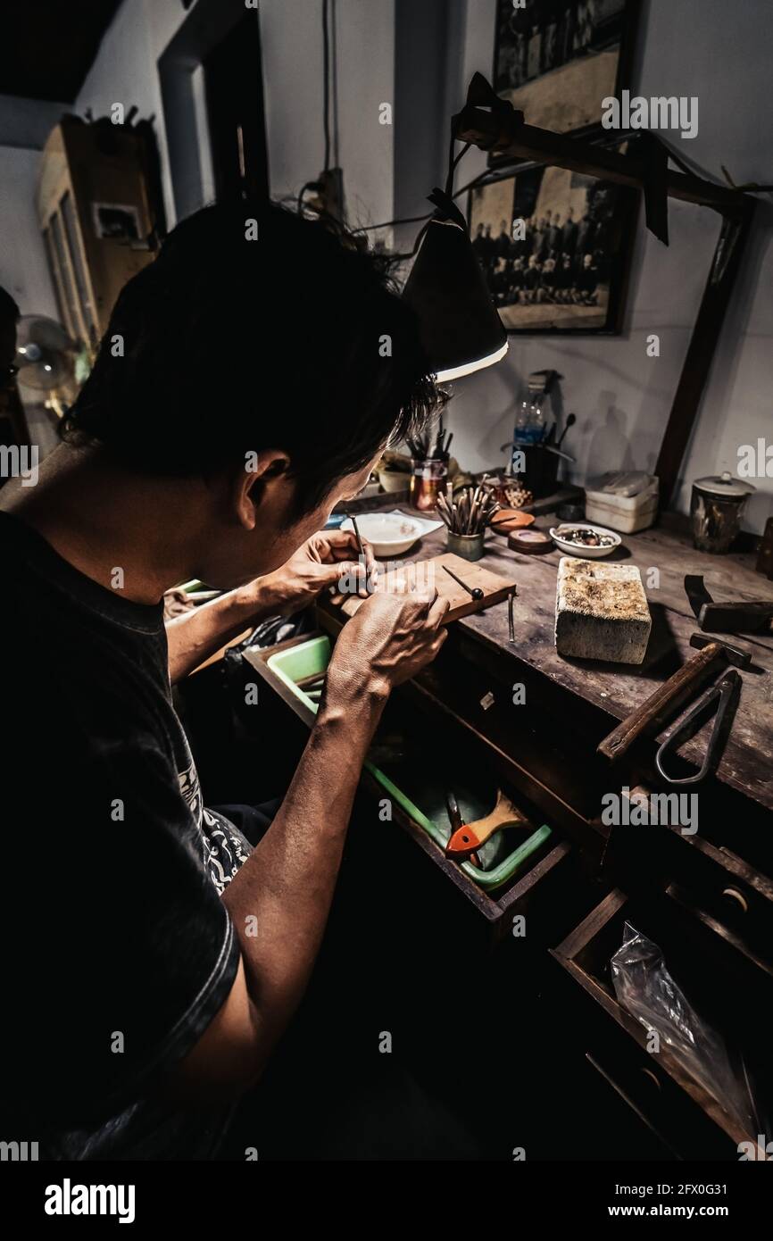 From above anonymous ethnic man working at weathered desk in craft ...