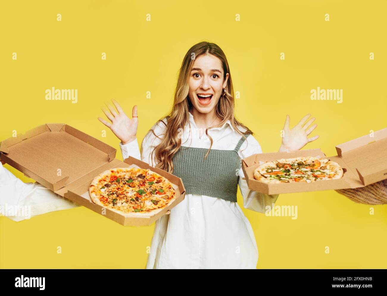 Emotional surprised young woman trying to choose pizza on yellow ...
