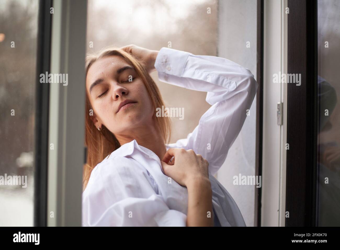 Portrait of a beautiful young blonde looking out of the window Stock ...