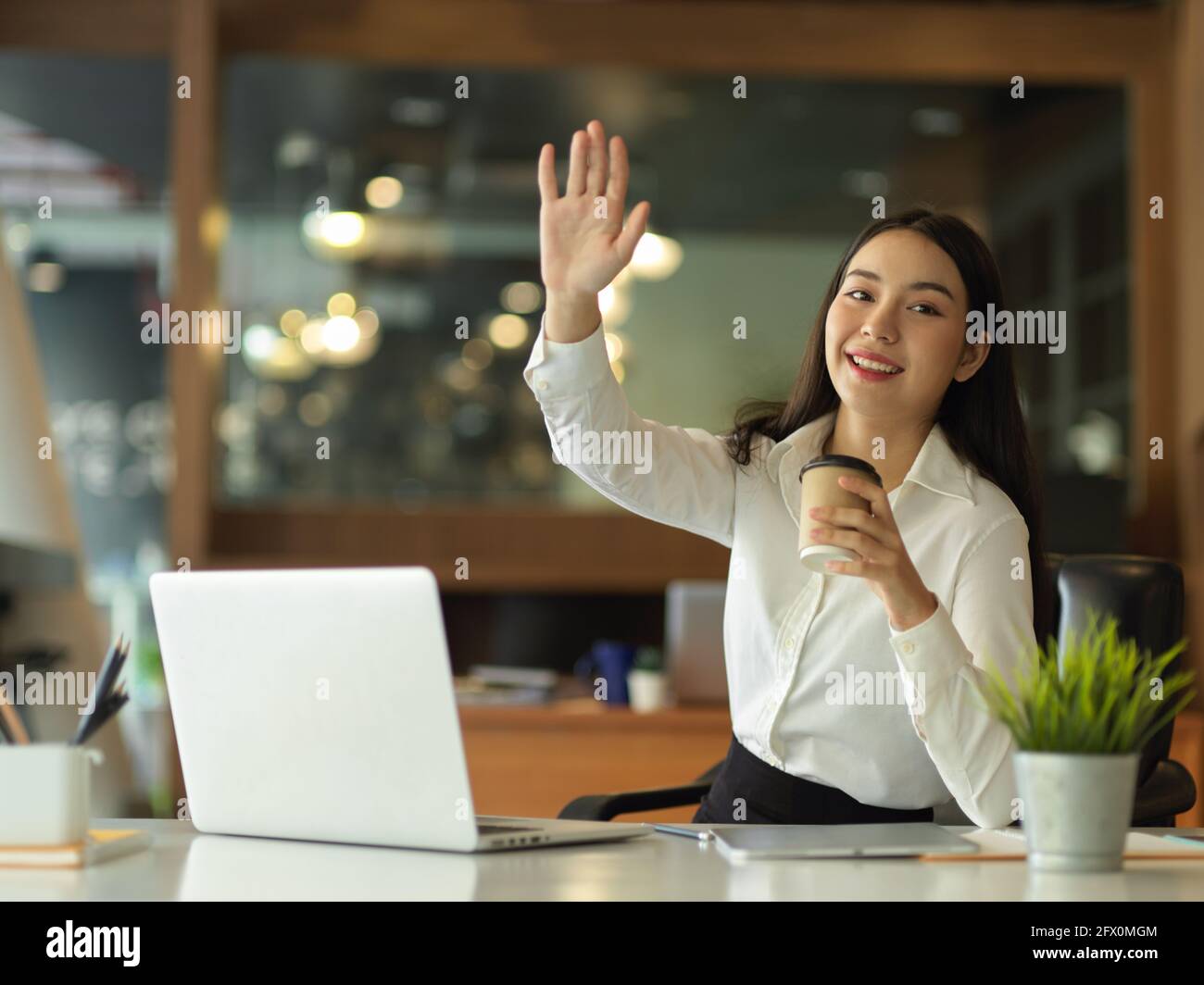 Portrait of female office worker holding paper cup and raising palm ...