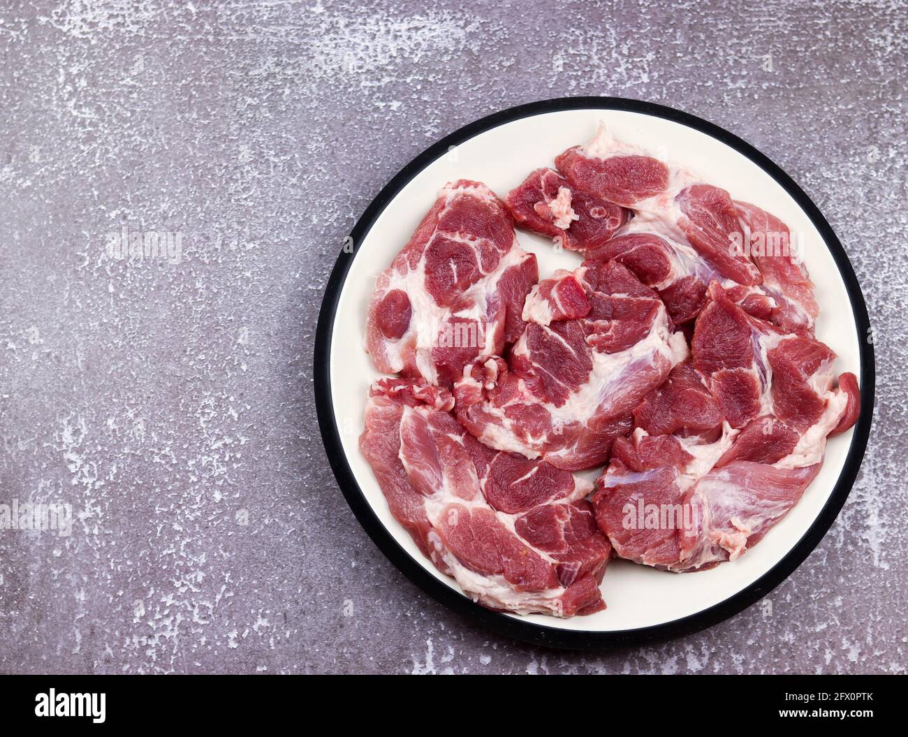 Raw blade steak from pork shoulder in a white plate on a dark wooden ...