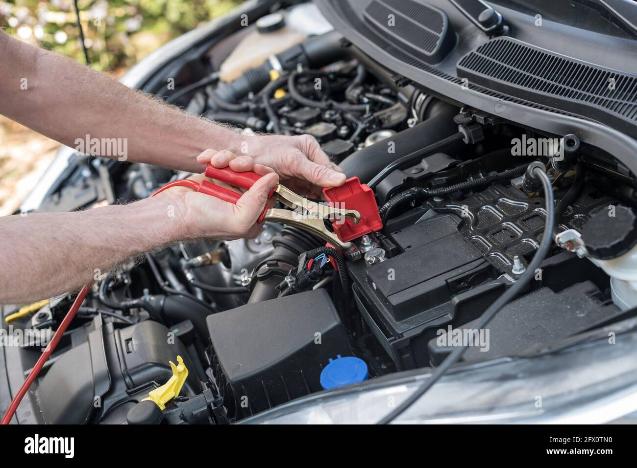 Hands of car mechanic using cables to start a car engine Stock Photo ...
